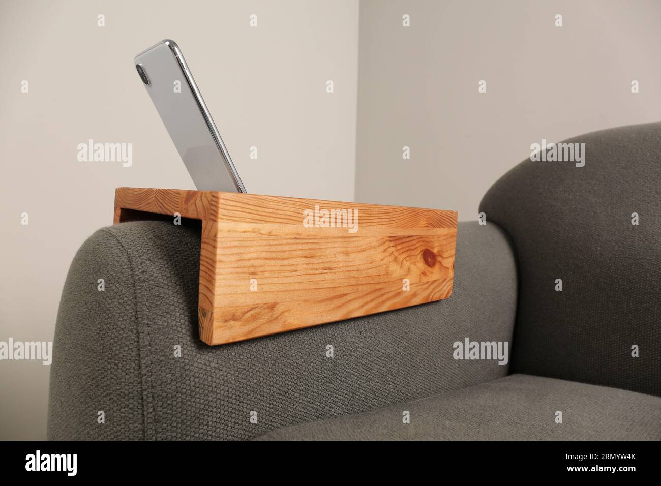 Smartphone on sofa with wooden armrest table in room. Interior element ...