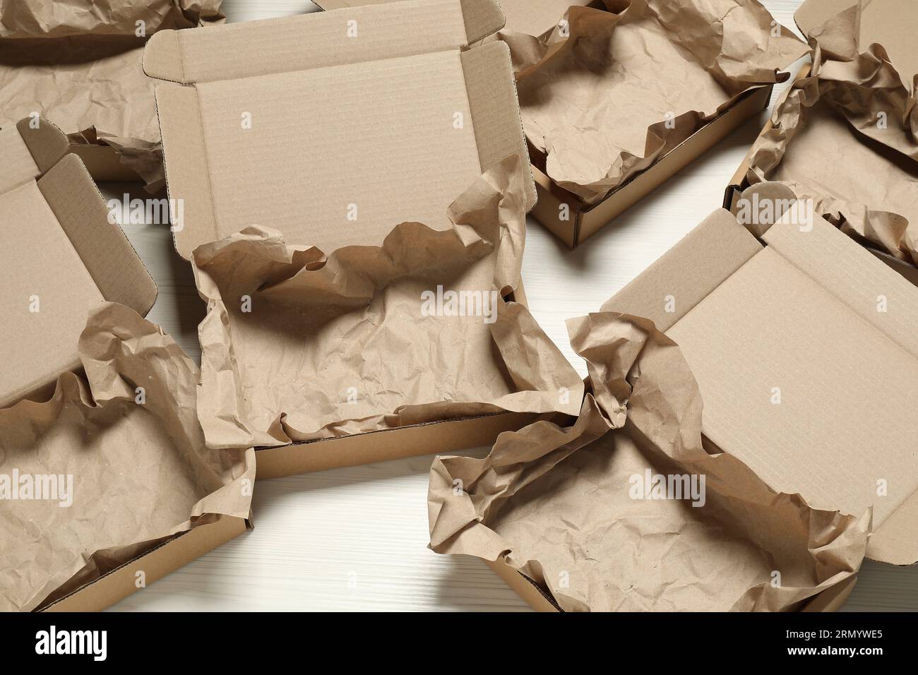 Many open cardboard boxes with crumpled paper on white wooden floor ...