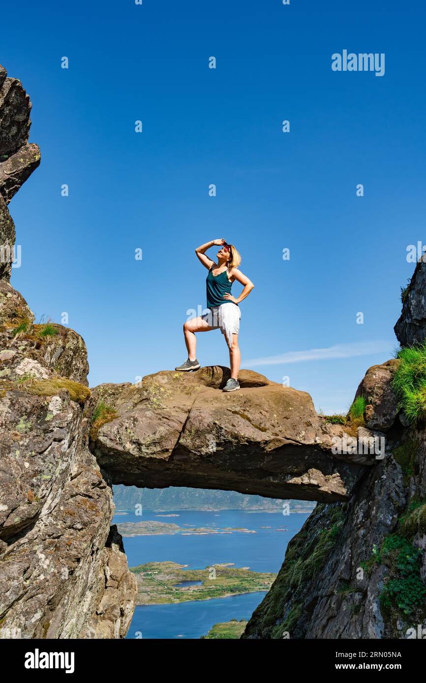Brave traveler woman standing on hanging stone between rocks ...