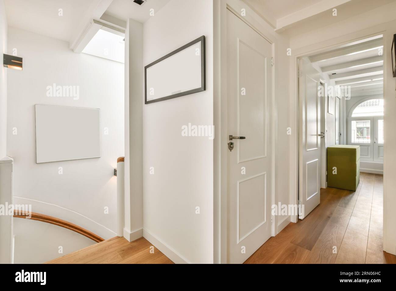 a hallway with white walls and wood flooring the room is well lit by ...