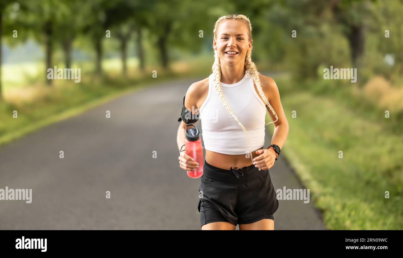 Female runner jogging outside in the park. Portrait of an athlete with ...