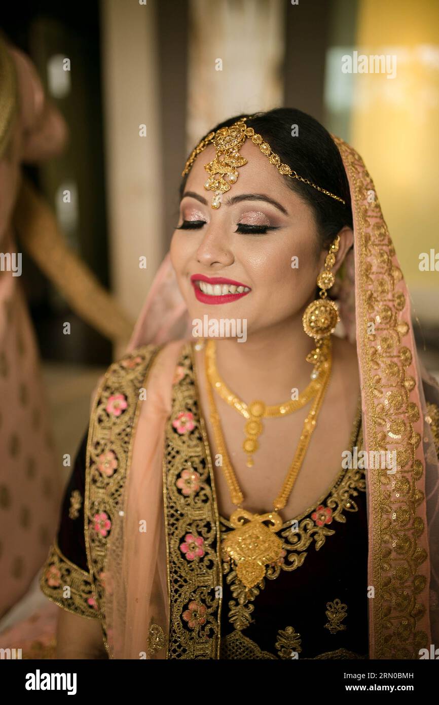 The radiant Nepali bride, draped in a resplendent red saree, warmly welcomes her groom with ...