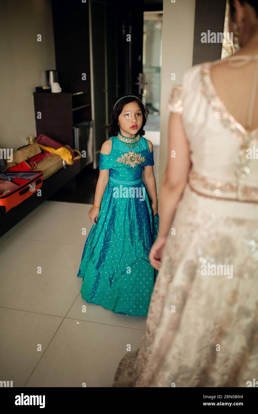 A little girl child in a blue party dress looking confused inside a ...