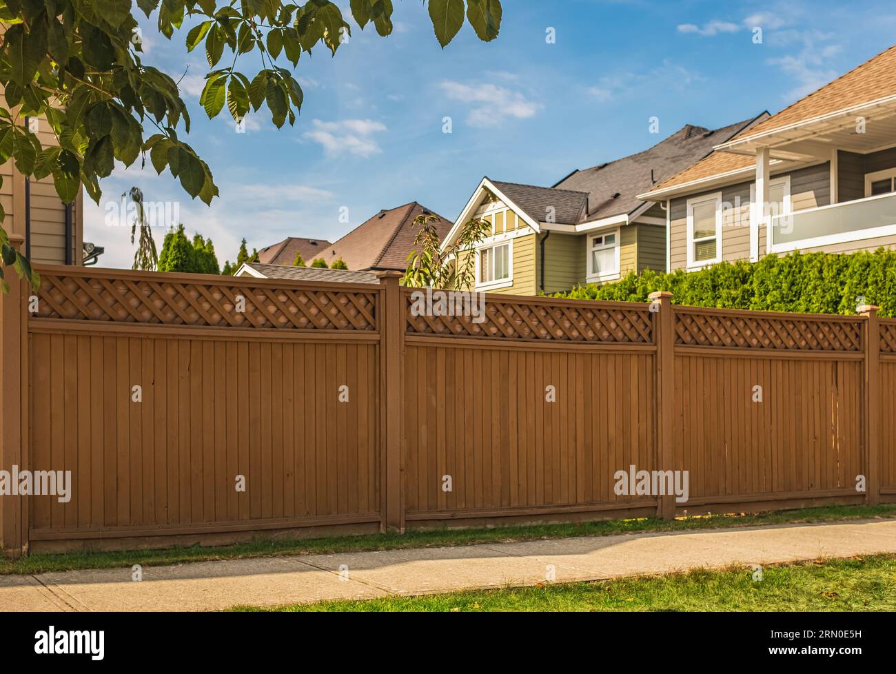 Nice new wooden fence around house. Wooden fence with green lawn in a ...