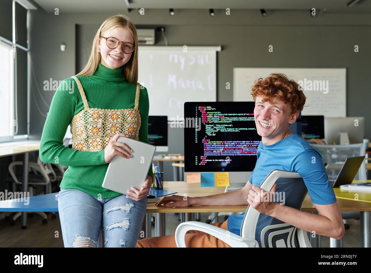 Portrait of classmates smiling at camera while having IT lesson at ...