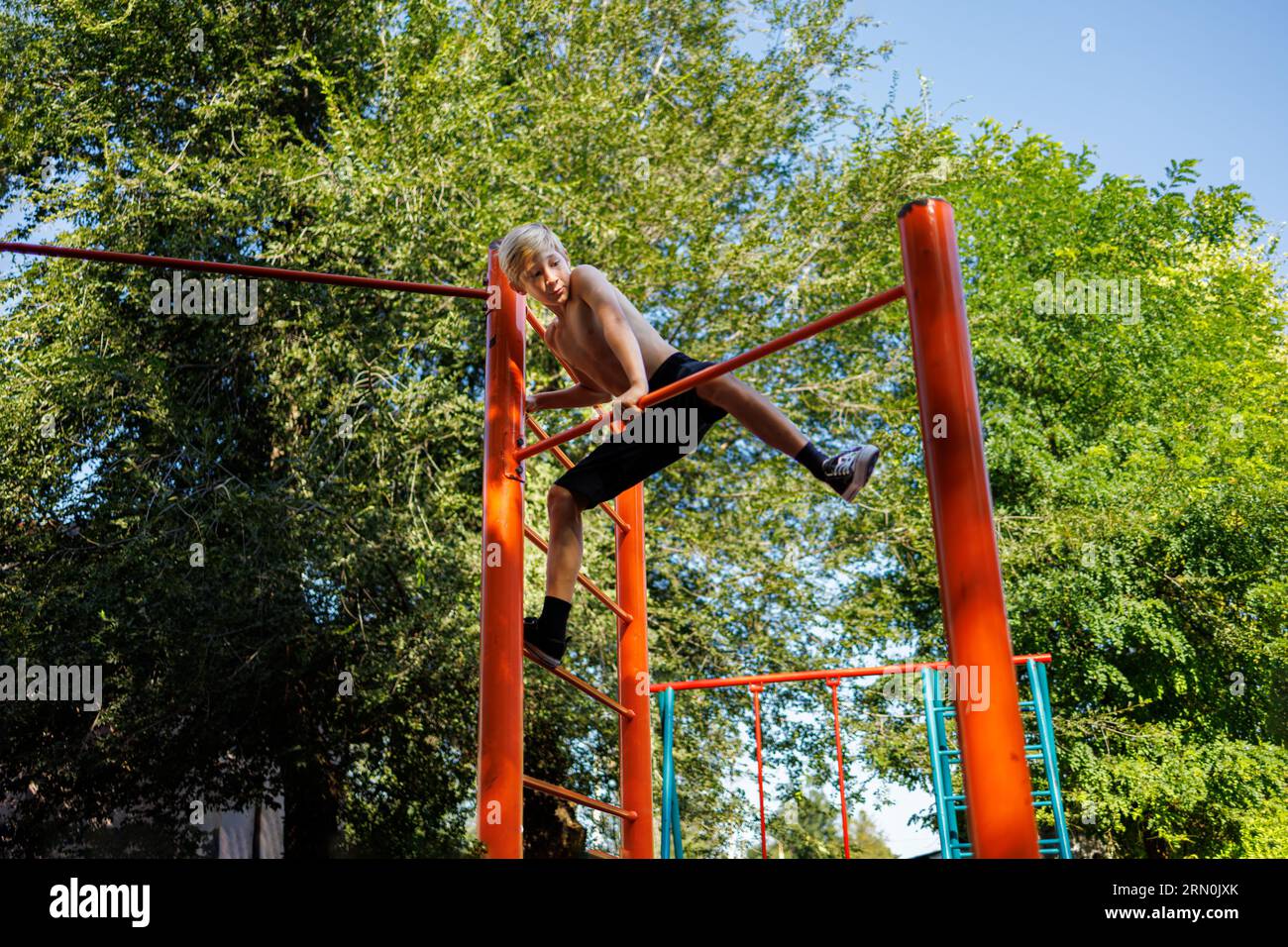 A boy athlete climbs a horizontal bar to perform a formal element ...