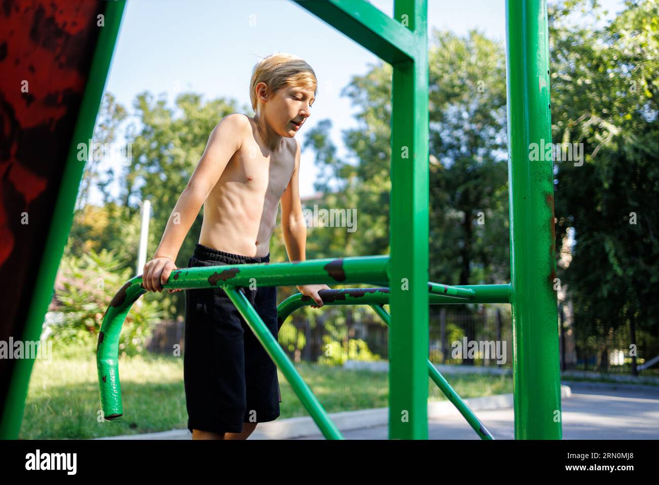 A sports child performs push-ups on sports bars. Street workout on a ...