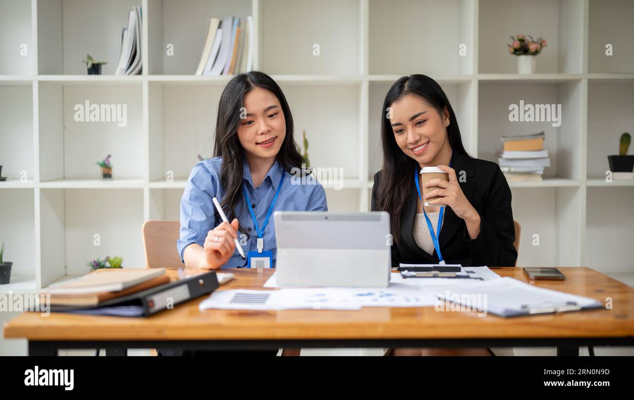 Two professional and happy Asian female accountants or businesswomen ...