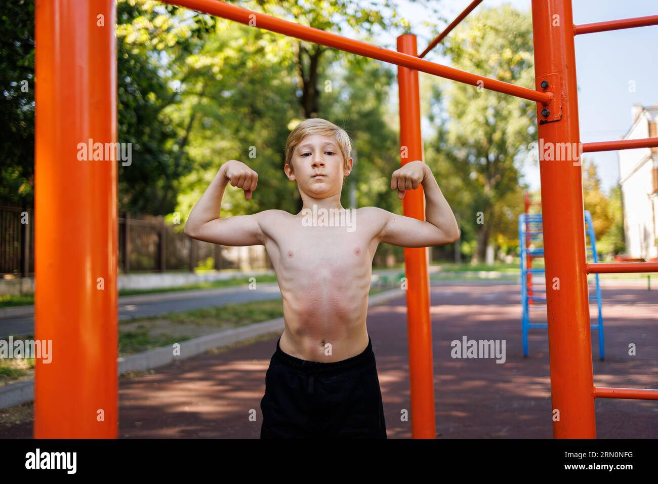 A teenage boy with an athletic build shows off his musculature. Street ...