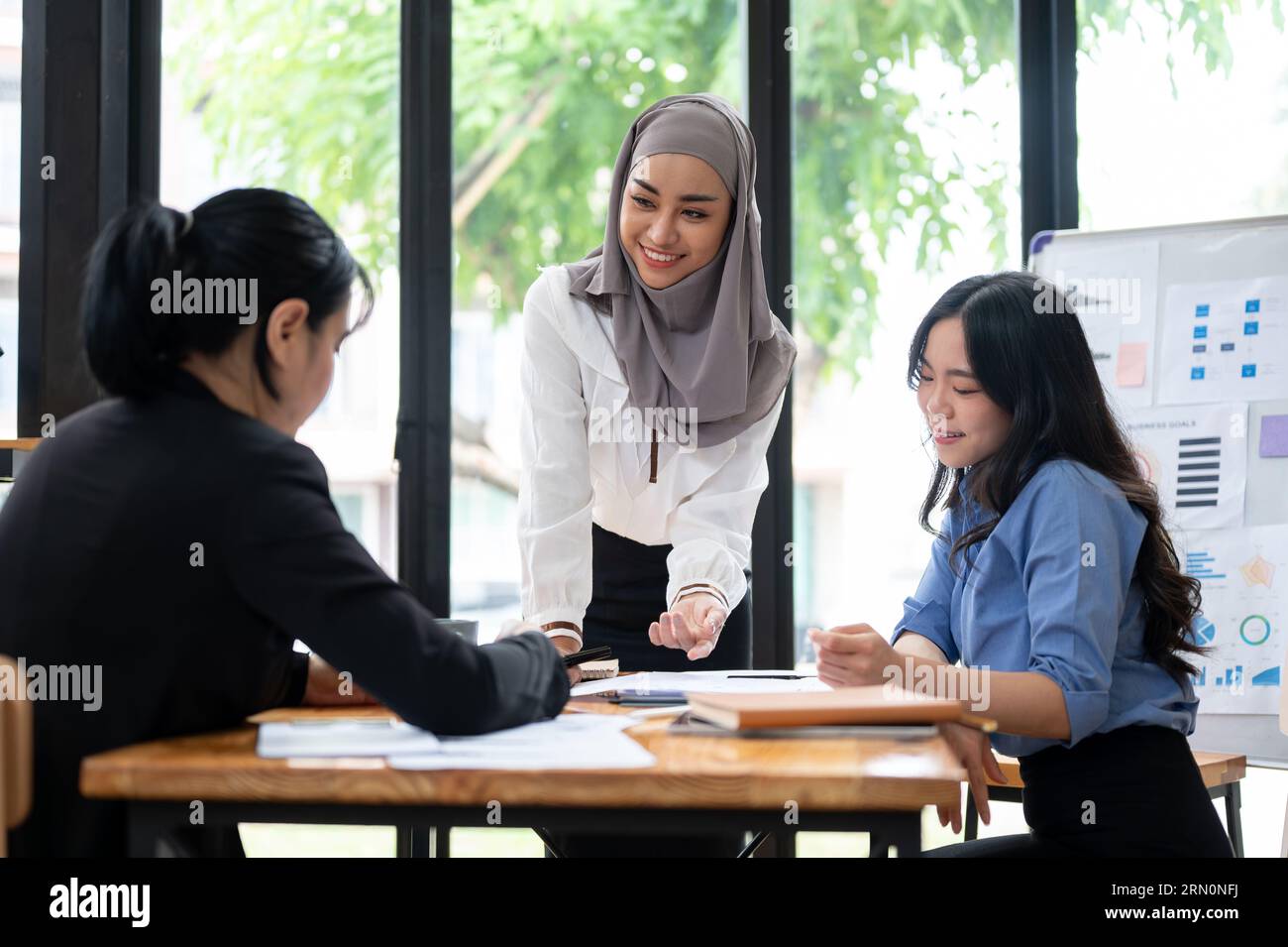 A beautiful and confident Asian Muslim female leader wearing a hijab is ...