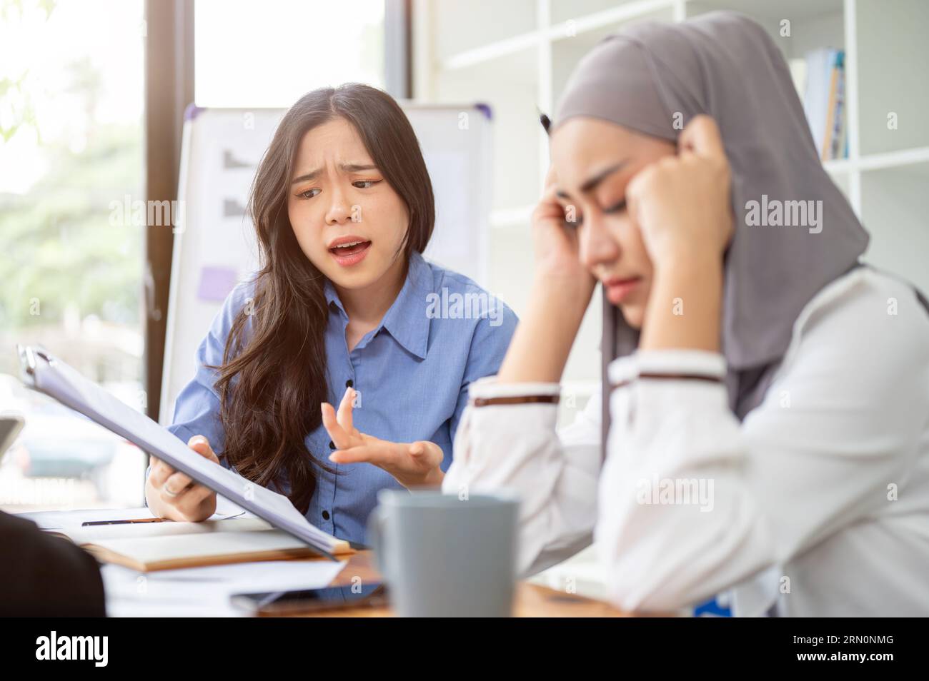 A dissatisfied and serious Asian businesswoman is complaining about the ...