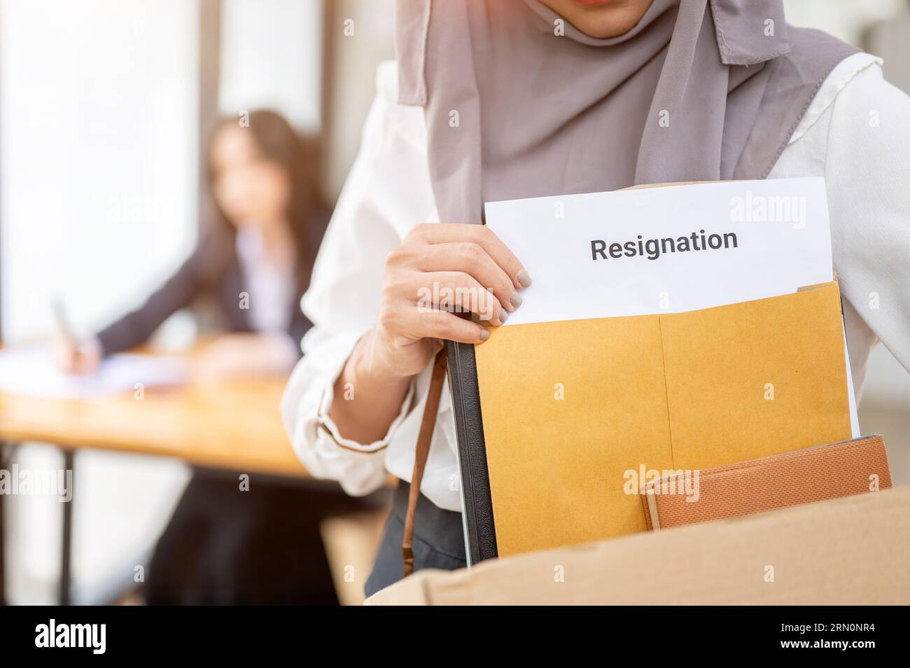 Sad and upset Asian Muslim female office worker wearing a hijab walks ...