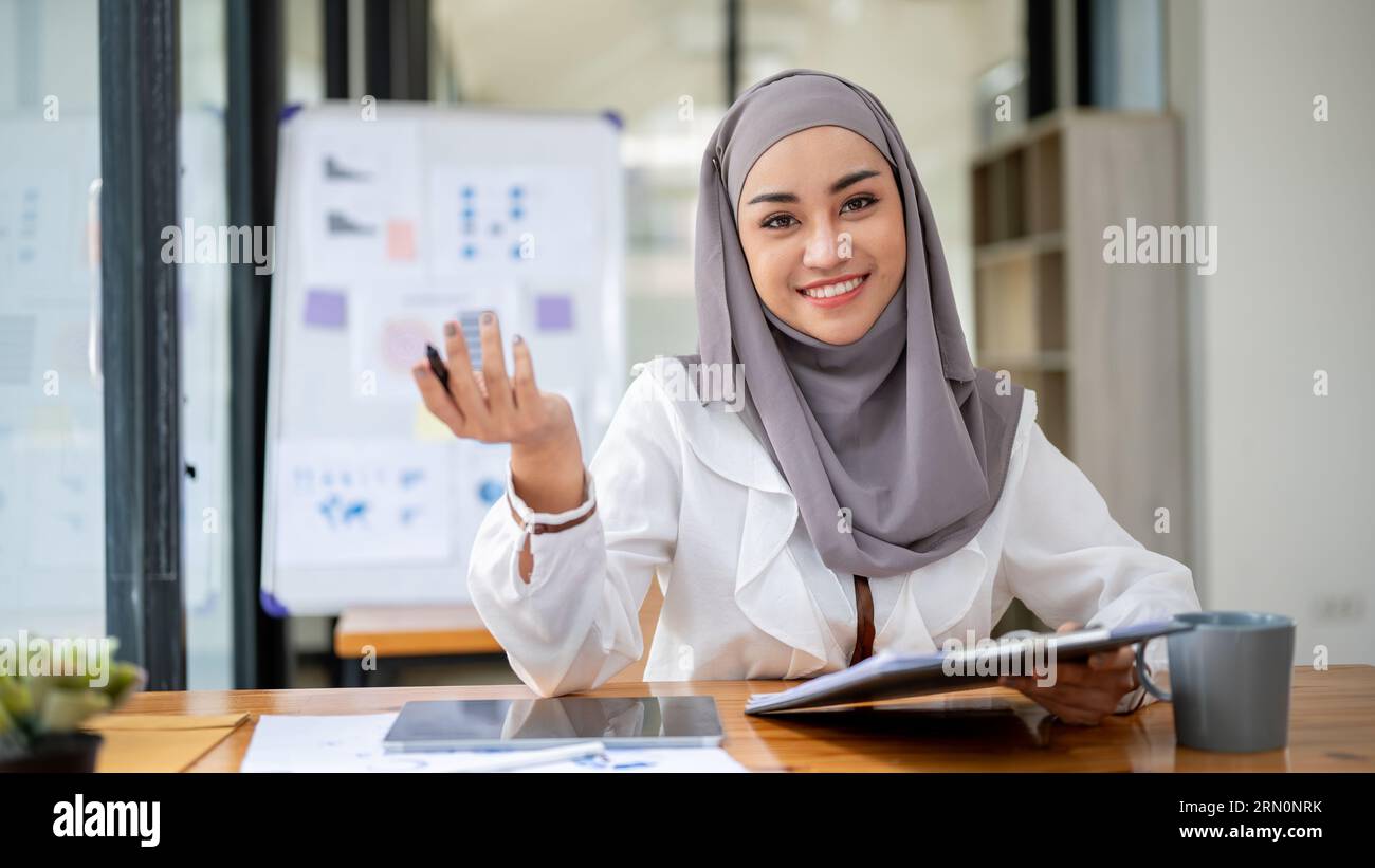 A portrait of a beautiful, smiling Asian Muslim businesswoman wearing a ...