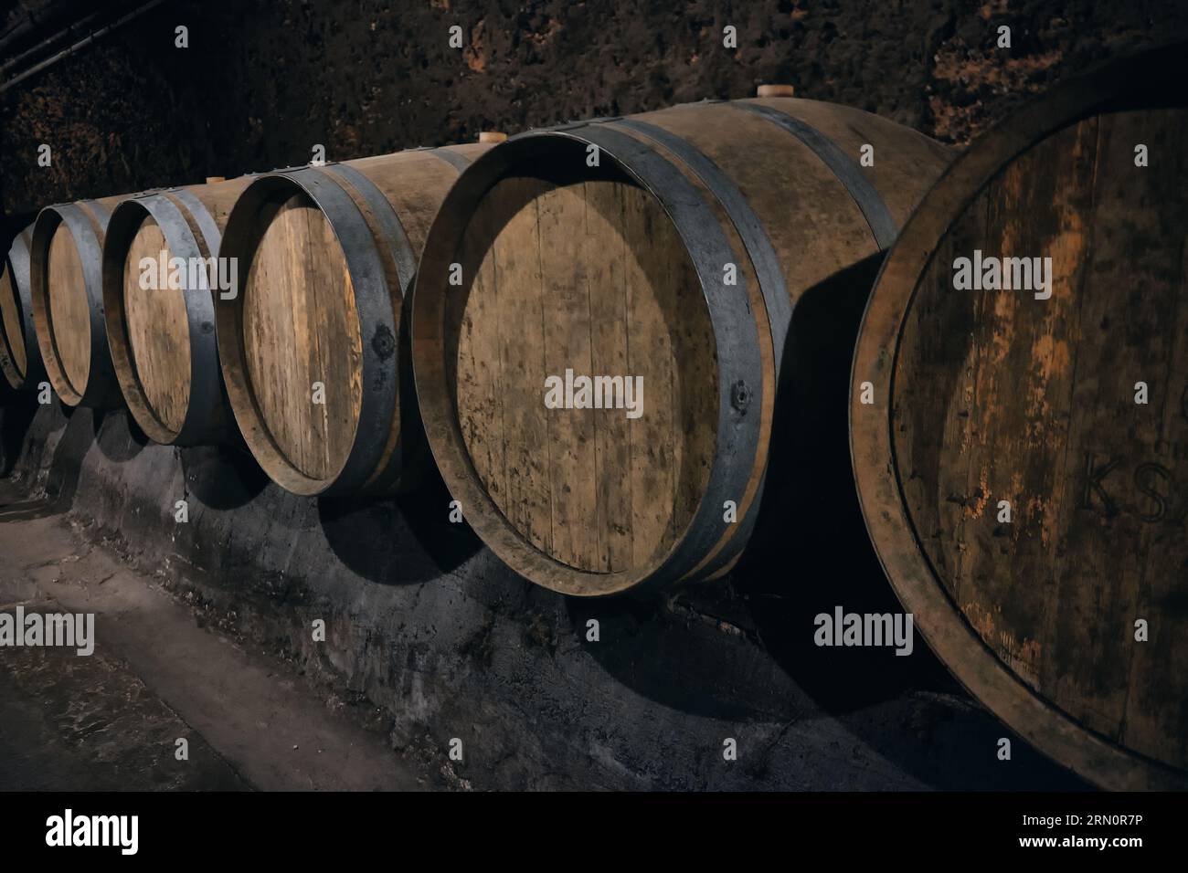 Row of wooden barrels bound with iron hoops in a bodega. Wine barrels ...