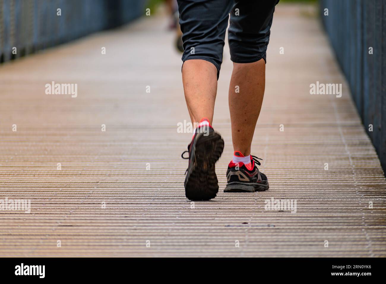Woman with running shoes walking on a bridge, helathy activity to make ...