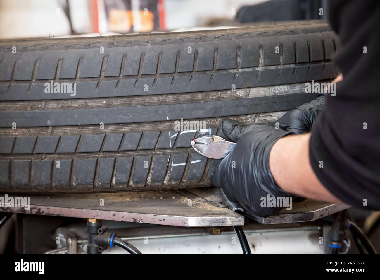 Tyre being repaired in a garage. Mechanic removing a nail from a tyre ...