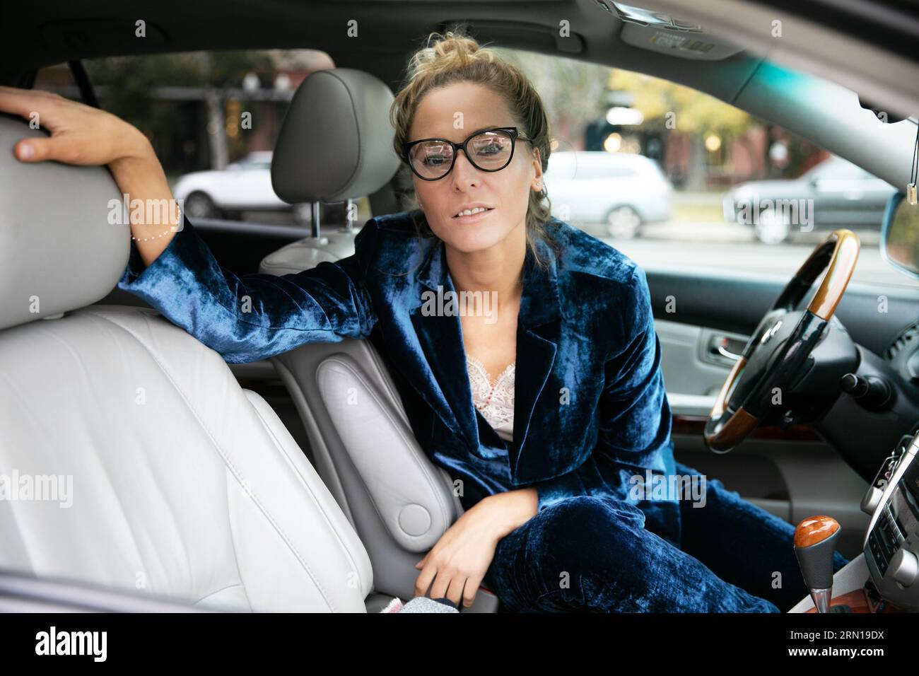 Beautiful blonde woman in glasses, in blue velvet pantsuit, poses for ...