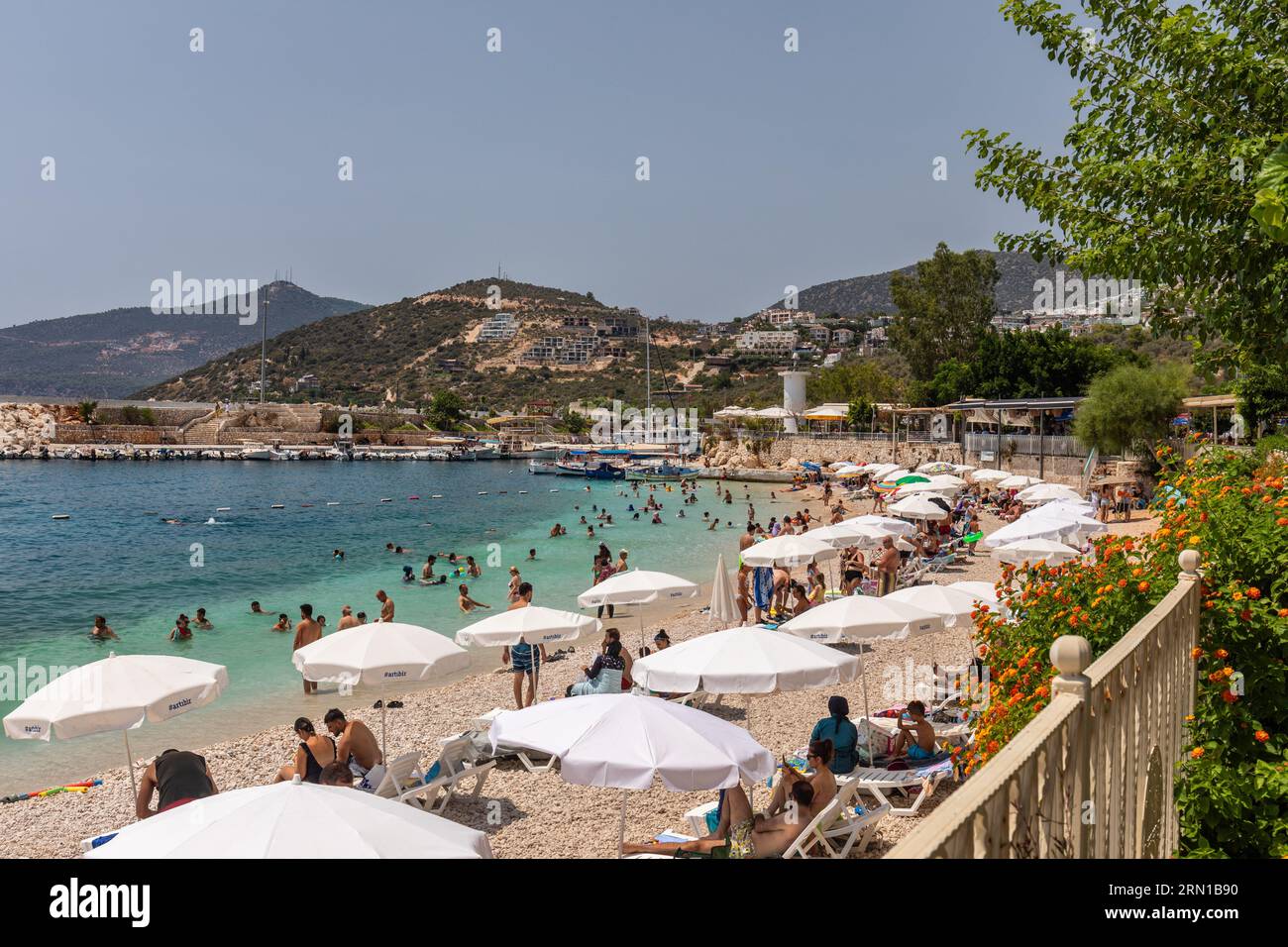 Kalkan pebbly beach filled with tourists, sun-loungers and beach ...