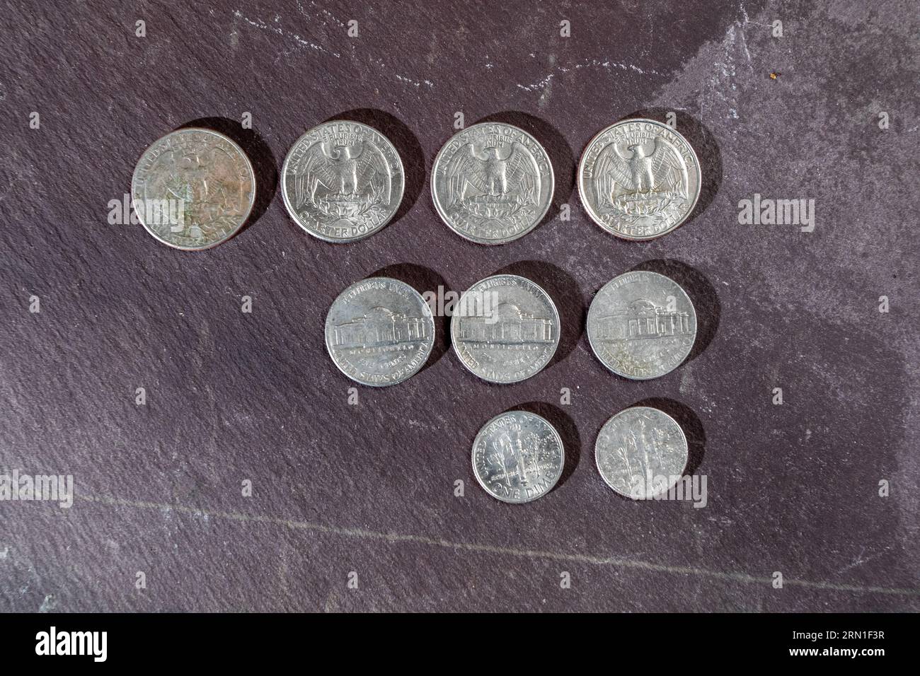 Reverse of nine American coins arranged in a pattern on a grey slate ...