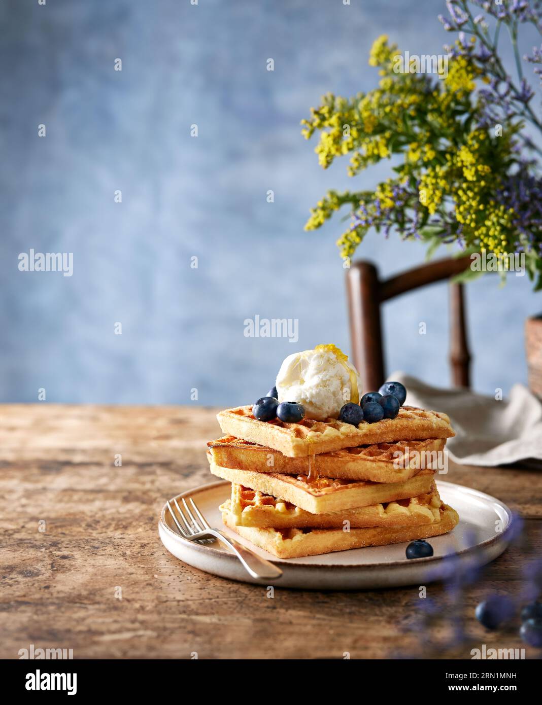 Waffles topped with blueberries, ice cream and honey standing on a ...