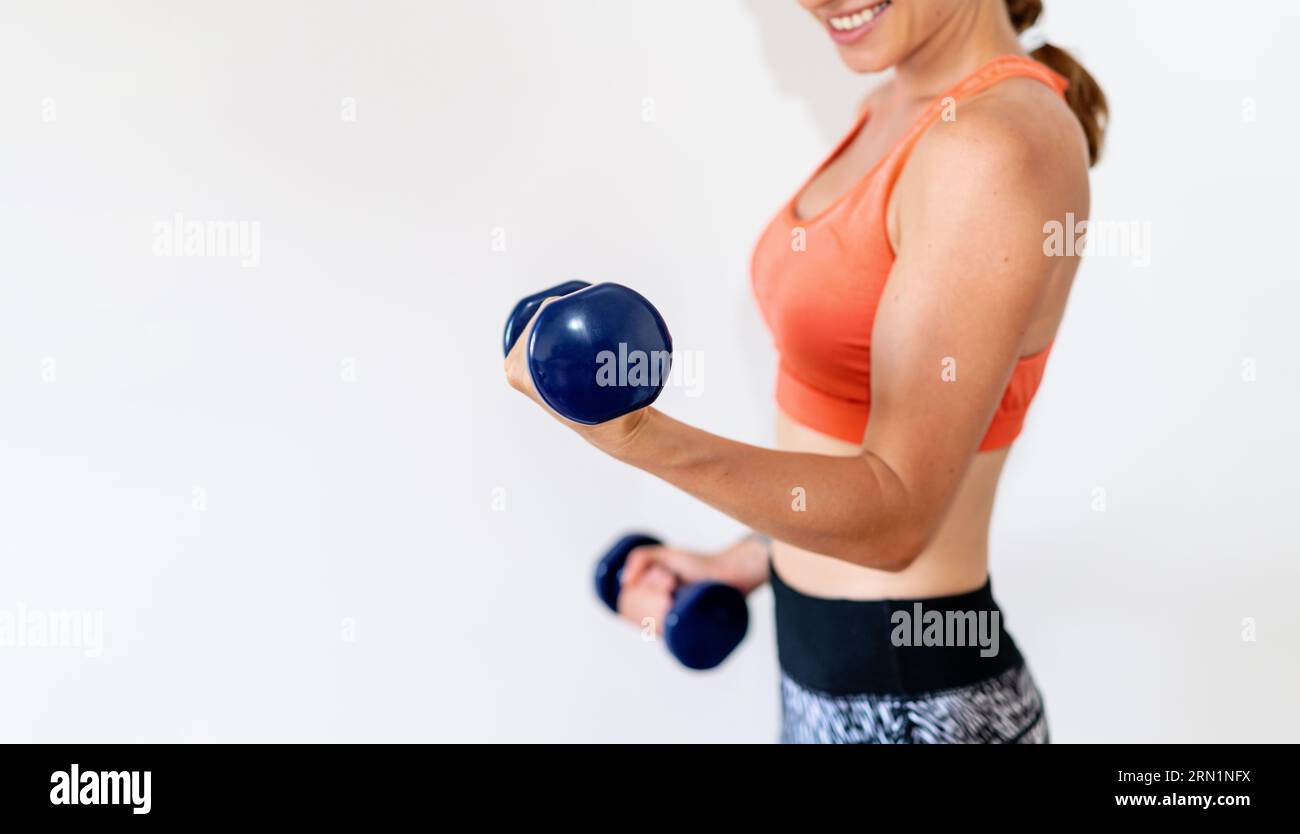 Slim sporty woman wearing sportswear doing biceps exercise using ...