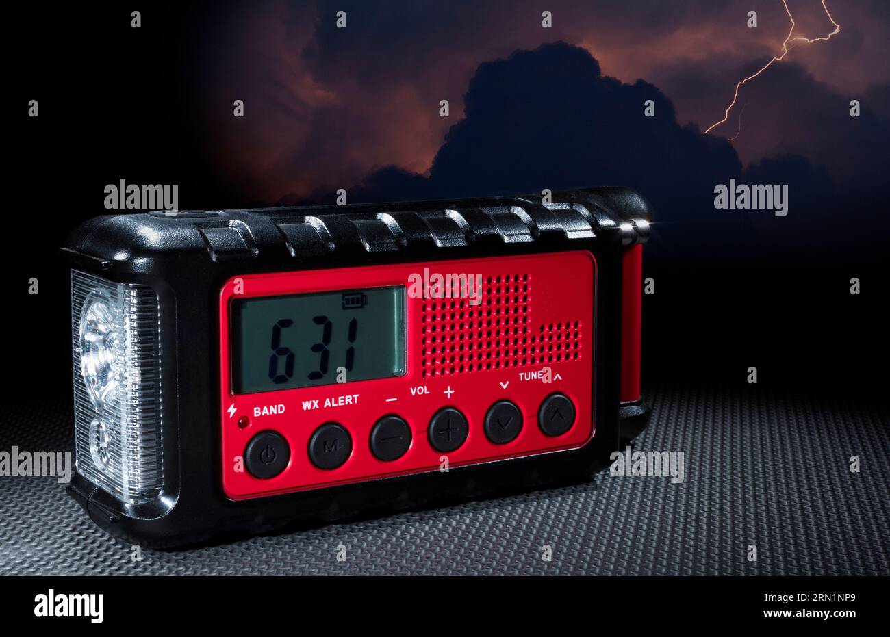 Electric storm behind a red weather radio that has a flashlight and ...