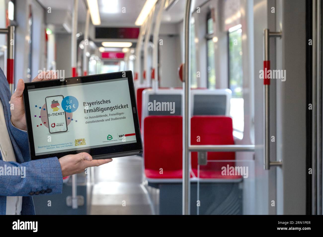 Nuremberg, Germany. 31st Aug, 2023. A man holds a tablet in a streetcar and advertises the ...