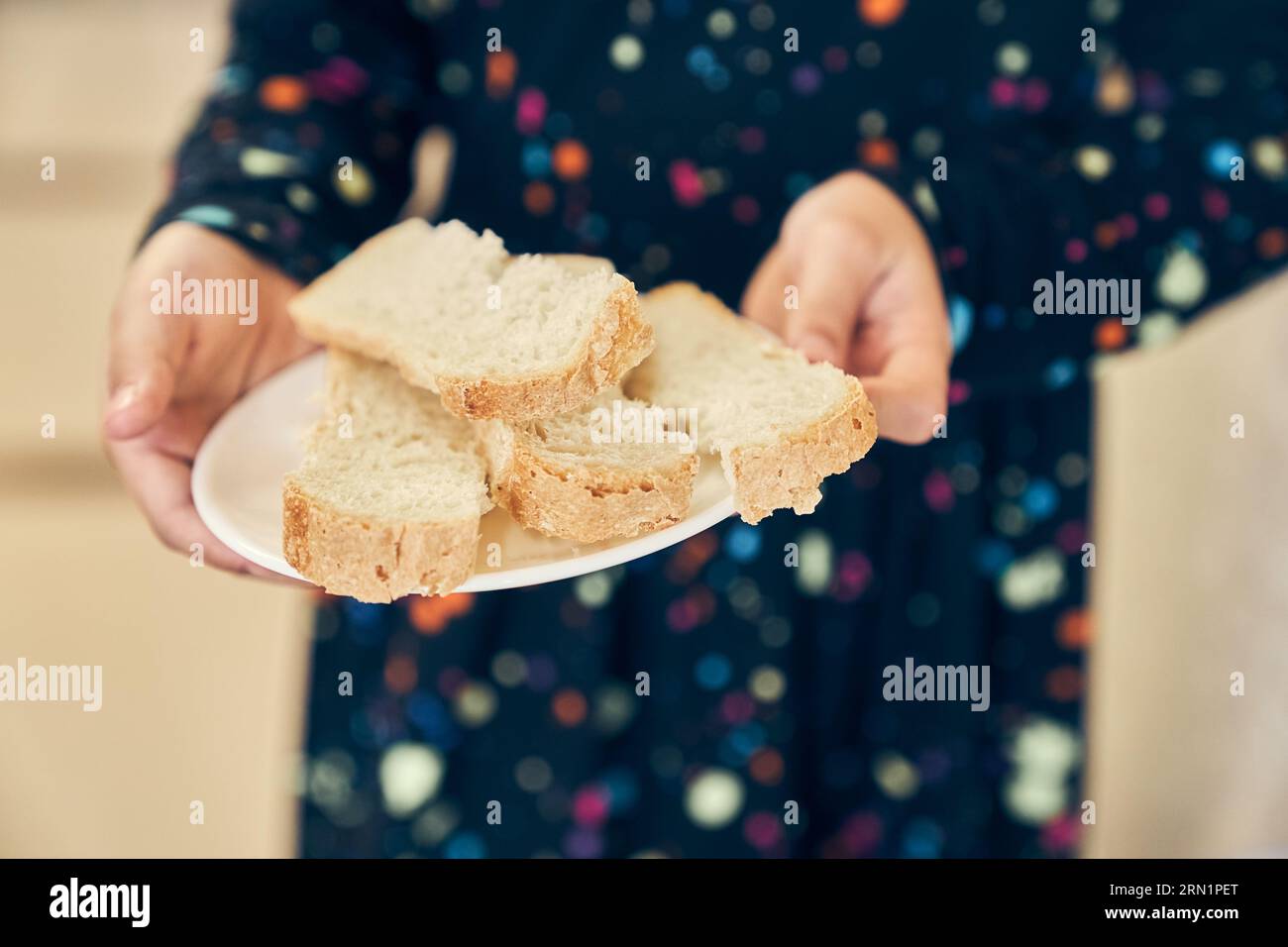 Child's hands hold a plate of bread. A traditional loaf of freshly ...
