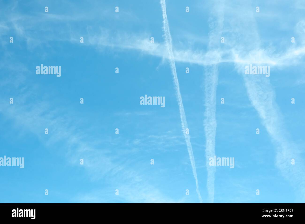 Cirrus clouds and long airplane trail row. Aero plane contrail in blue cloudy sky background ...