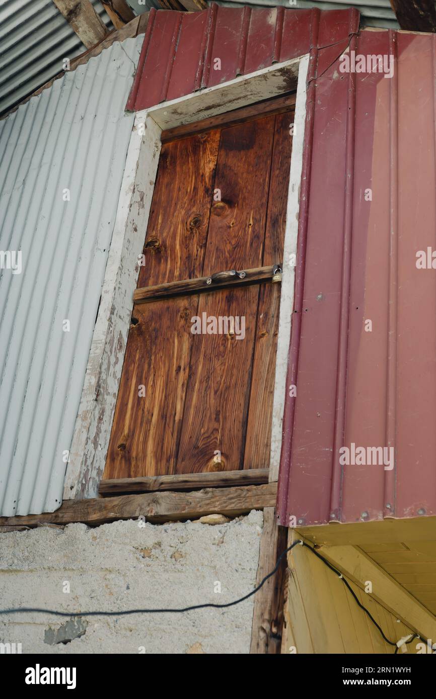 A two-story wooden and metal-clad building with a large wooden door ...