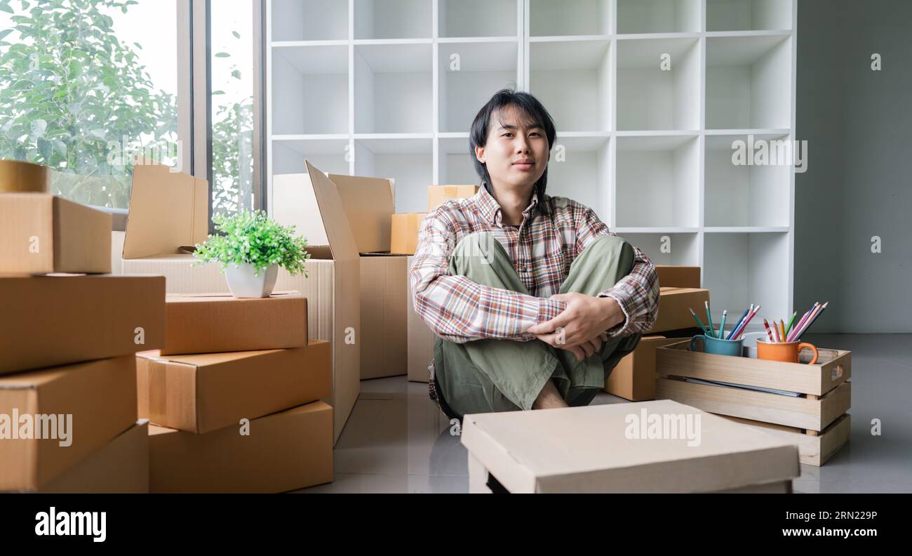 Handsome asian man in casual clothes siting leaning on pile of large ...