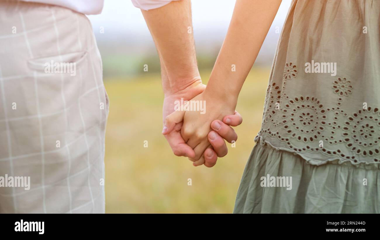 Couple of man and woman walk hand in hand across field Stock Photo - Alamy