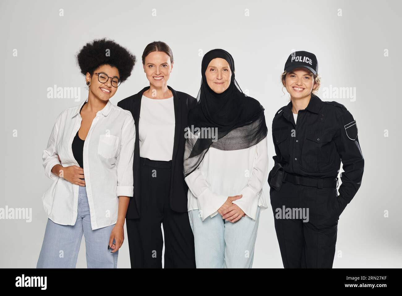 cheerful group of multiethnic women posing together isolated on grey ...