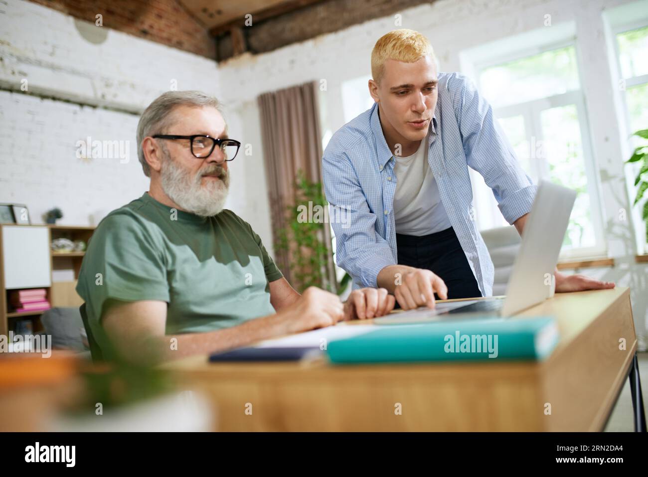 Cooperation of adults and youngsters. Young man helping senior ...