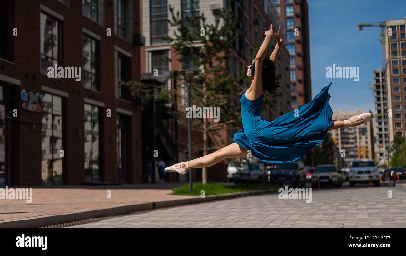 Beautiful Asian ballerina dancing outdoors. Urban landscape. Grand jete ...