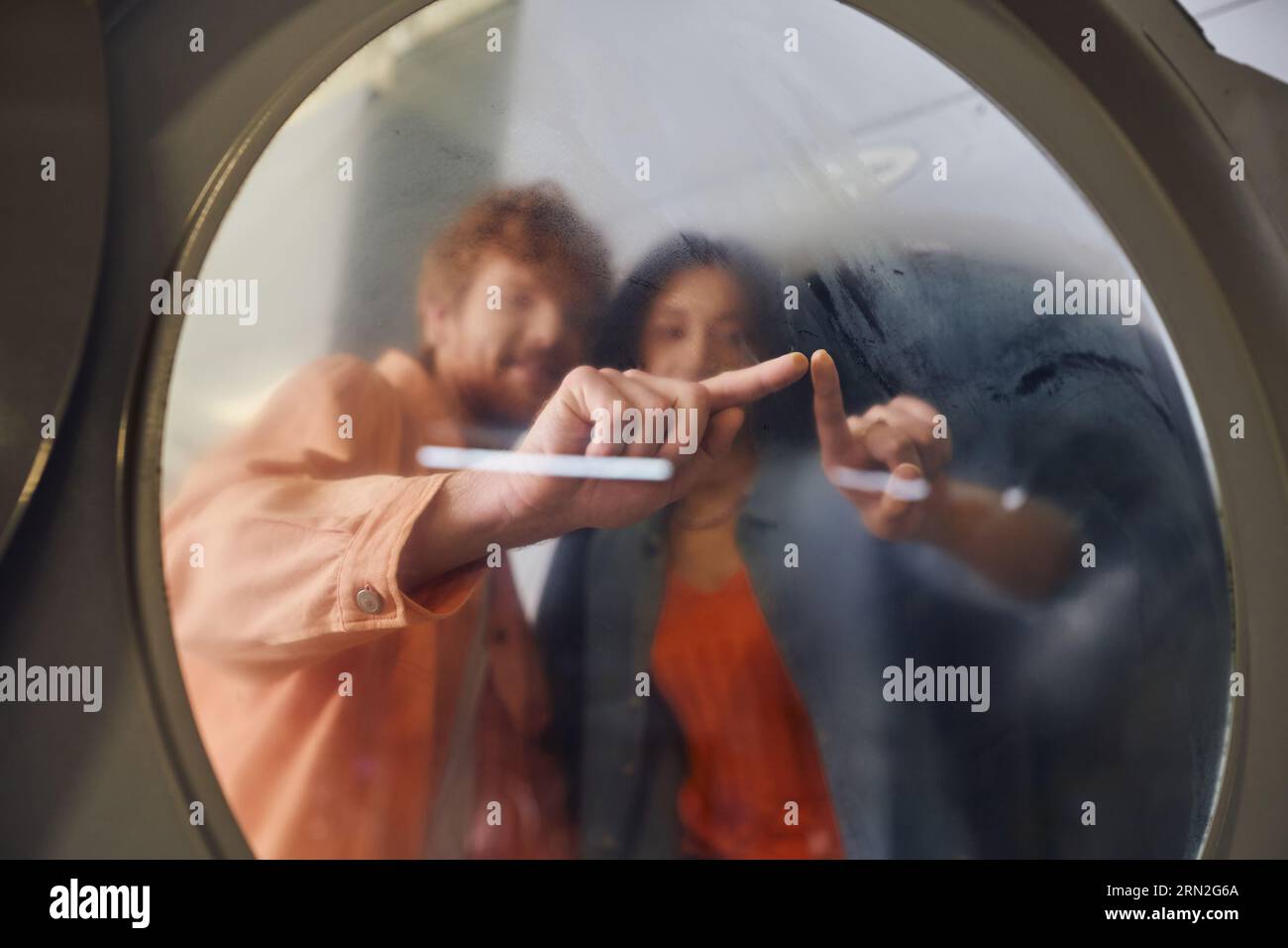 blurred young romantic couple touching glass of washing machine in ...