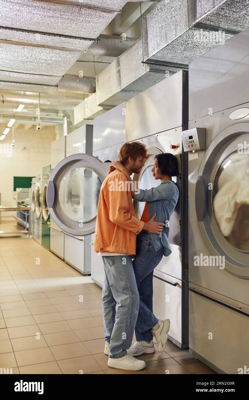 side view of young romantic multiethnic couple hugging near washing ...