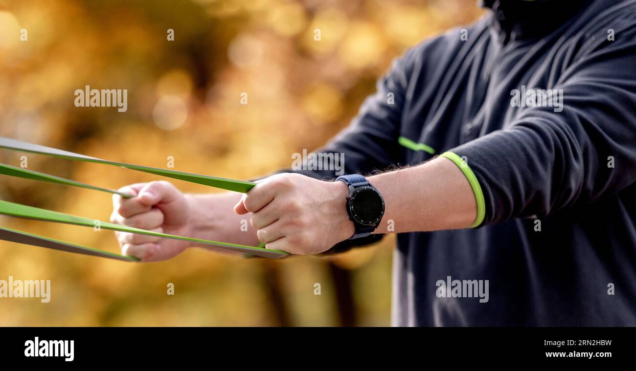 Strong man guy training with elastic rubber band at the stadium ...