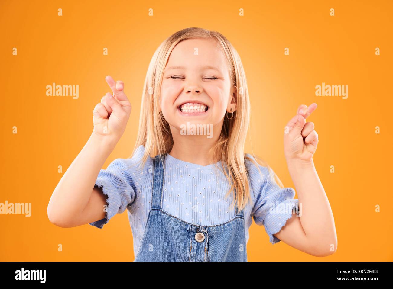Child, fingers crossed and wish or hope in studio for luck, prayer or ...