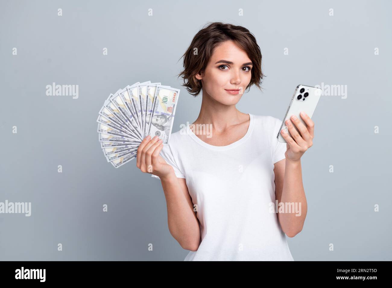 Photo of pretty successful girl hold dollar bills banknotes use smart ...