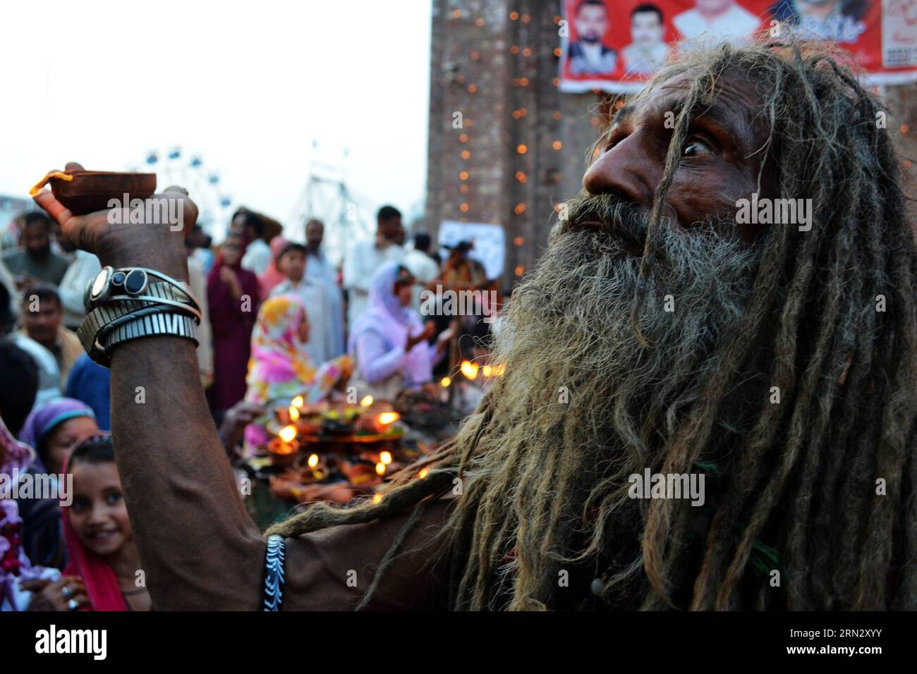 A Pakistani devotee carries an oil lamp at the shrine of Muslim Sufi saint Shah Hussain ...