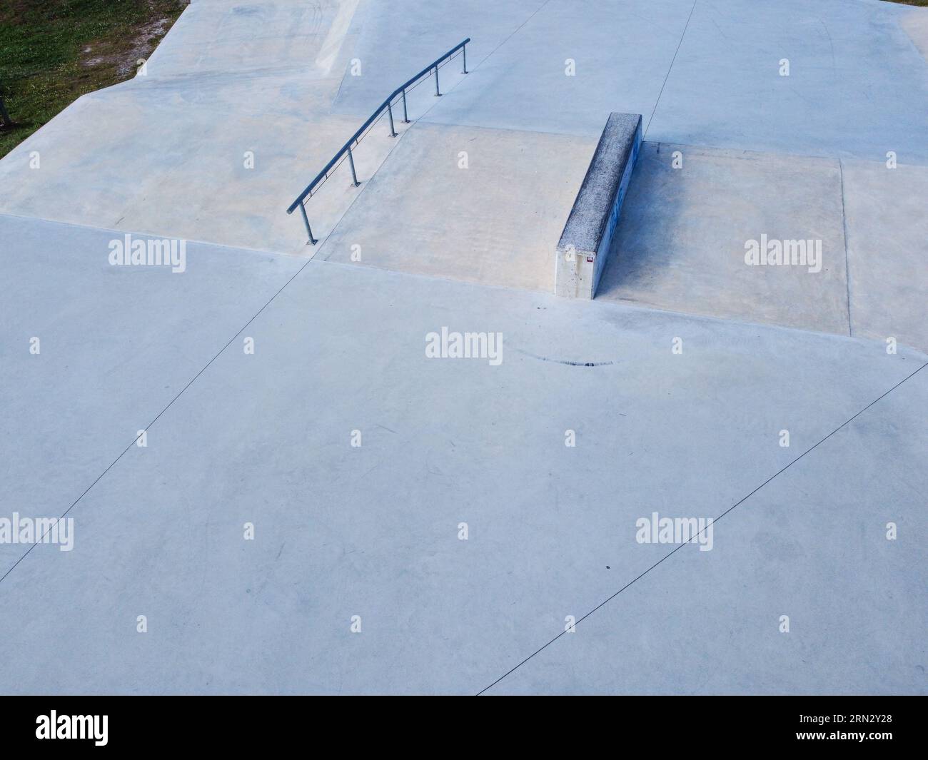 Aerial view with drone of a public skatepark near the sea. Sloped metal ...