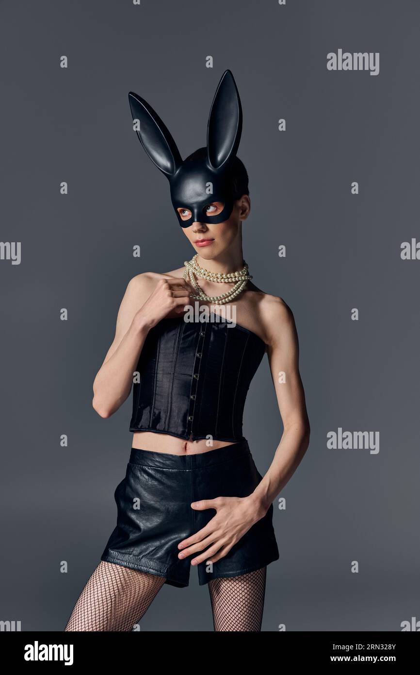 queer model in corset posing in bdsm bunny mask on grey, pearl necklace ...