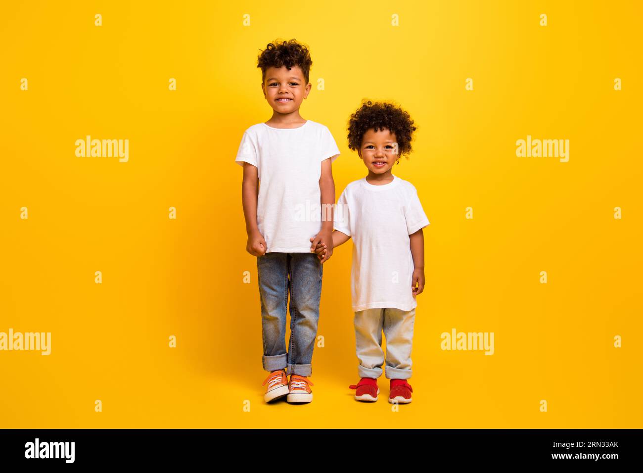 Full length portrait of two positive friendly cute brothers hold arms ...