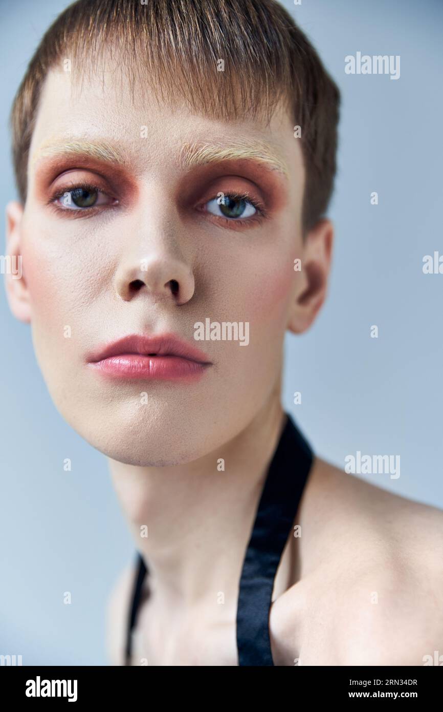 close up, androgynous person with makeup, grey backdrop, beauty and ...