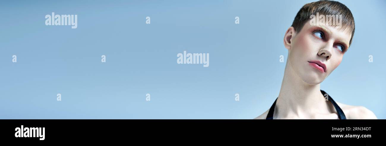 portrait, androgynous model with makeup looking away on grey, beauty ...