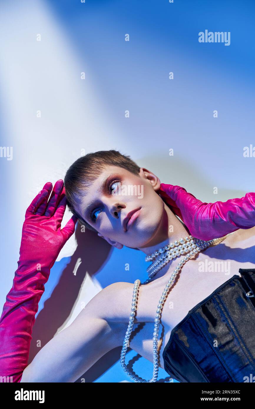 top view, genderqueer model in corset and pink gloves looking away and ...