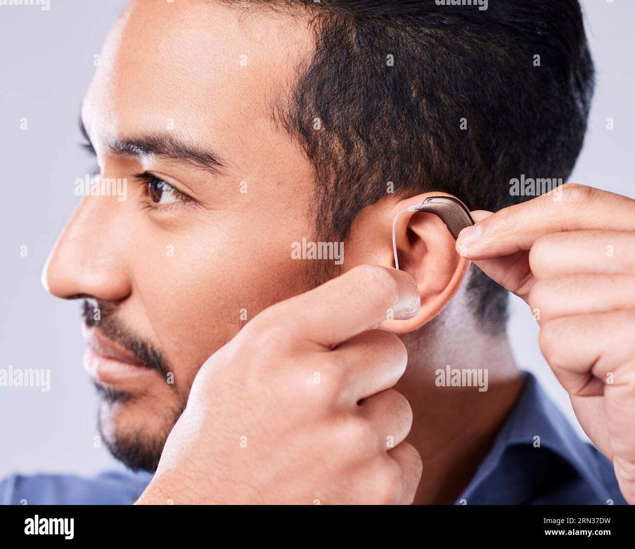 Deaf, cochlear and asian man ear in studio with hearing aid, audio and ...