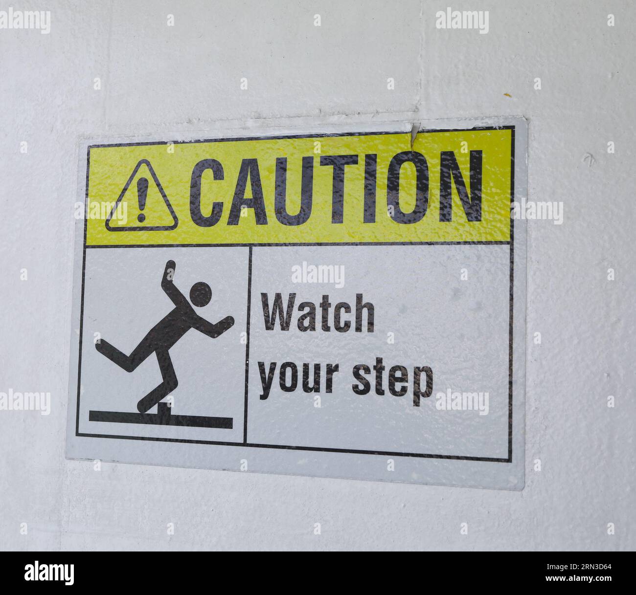 Yellow and black warning sign on stairs stating "Watch your Step ...