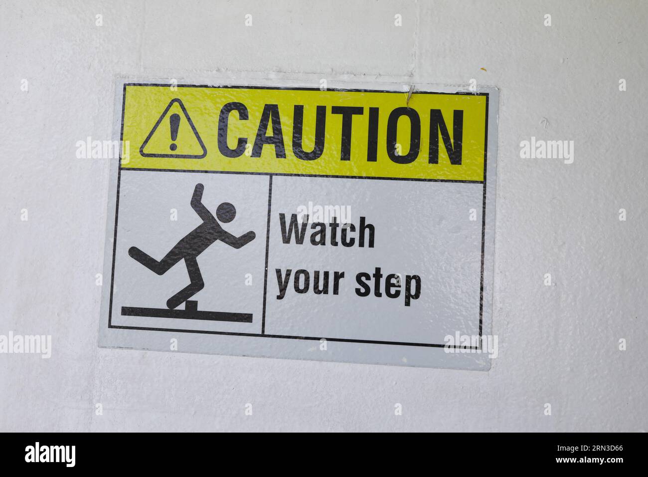 Yellow and black warning sign on stairs stating "Watch your Step ...